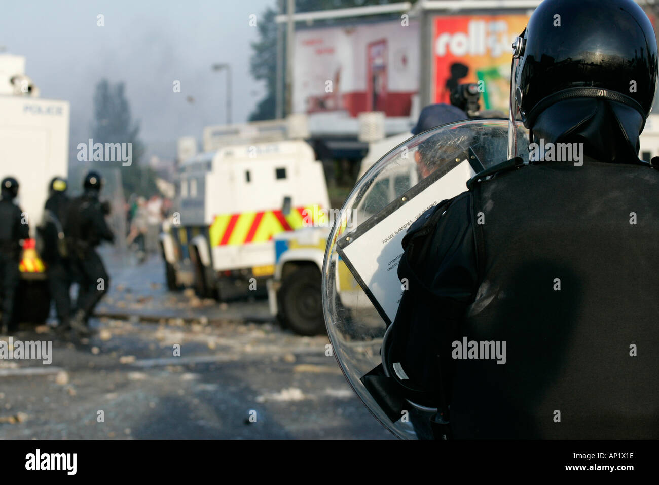 PSNI riot officer with baton round warning on shield watches rioting on ...