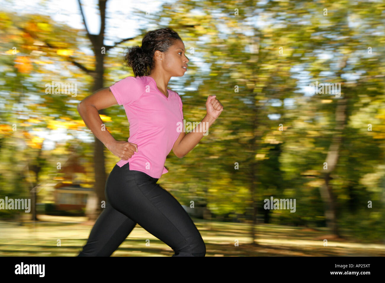 Young woman, jogging, running on a street with trees fall colors autumn ...