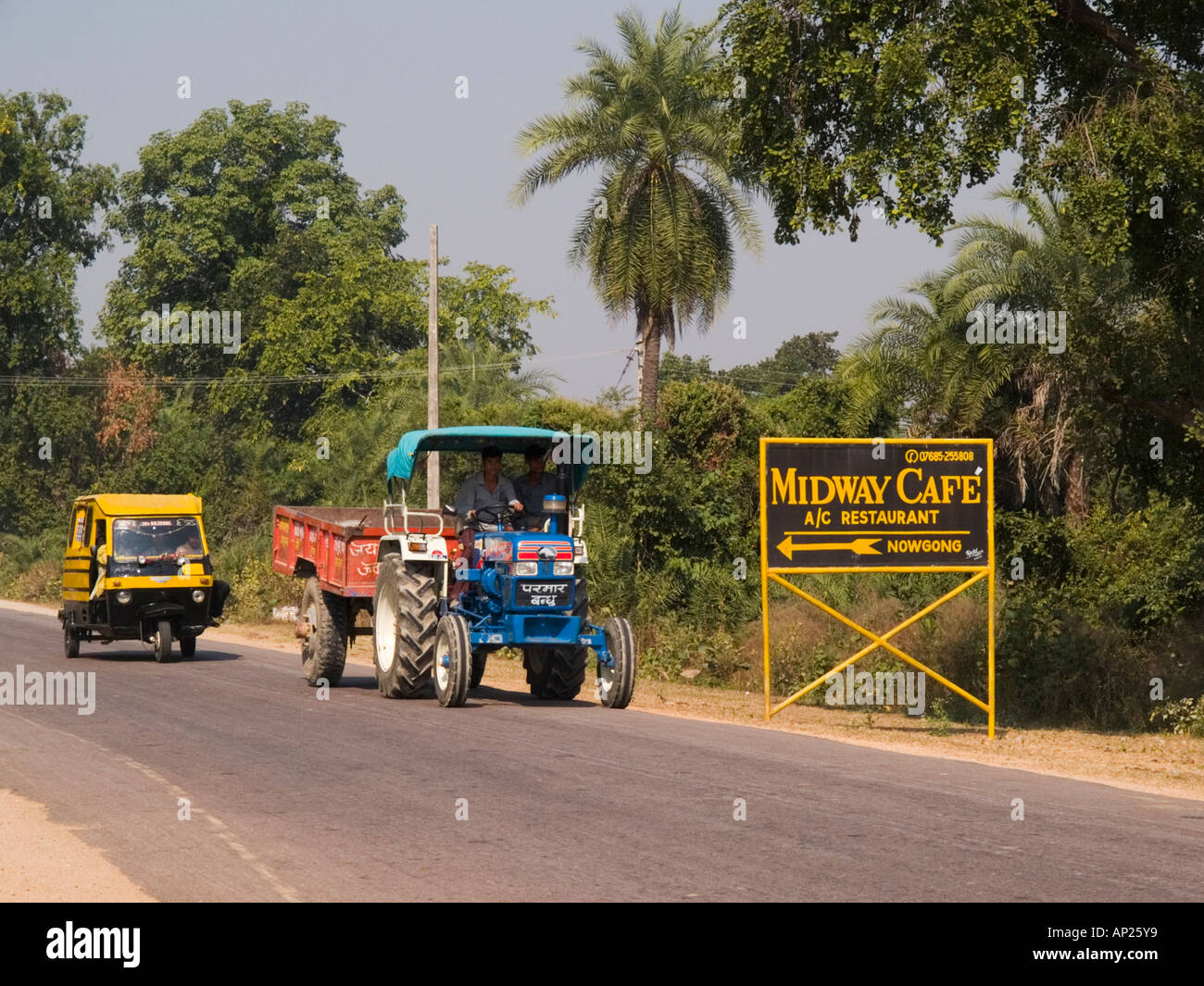 Three Wheeled Auto Rickshaw taxi and local tractor and trailer passing ...