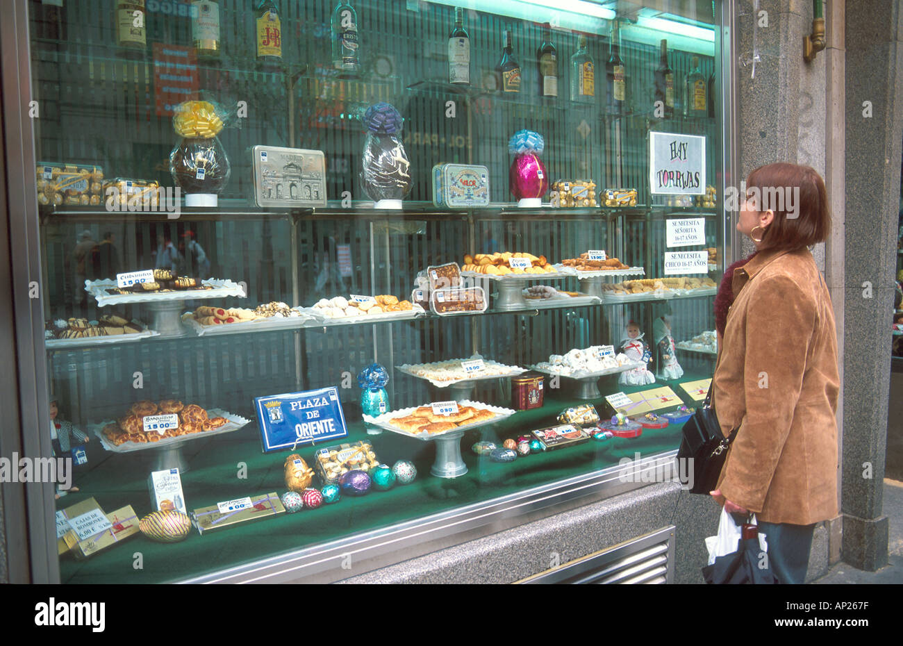 Woman looking through a bakery window at pastrie sand and candy in ...