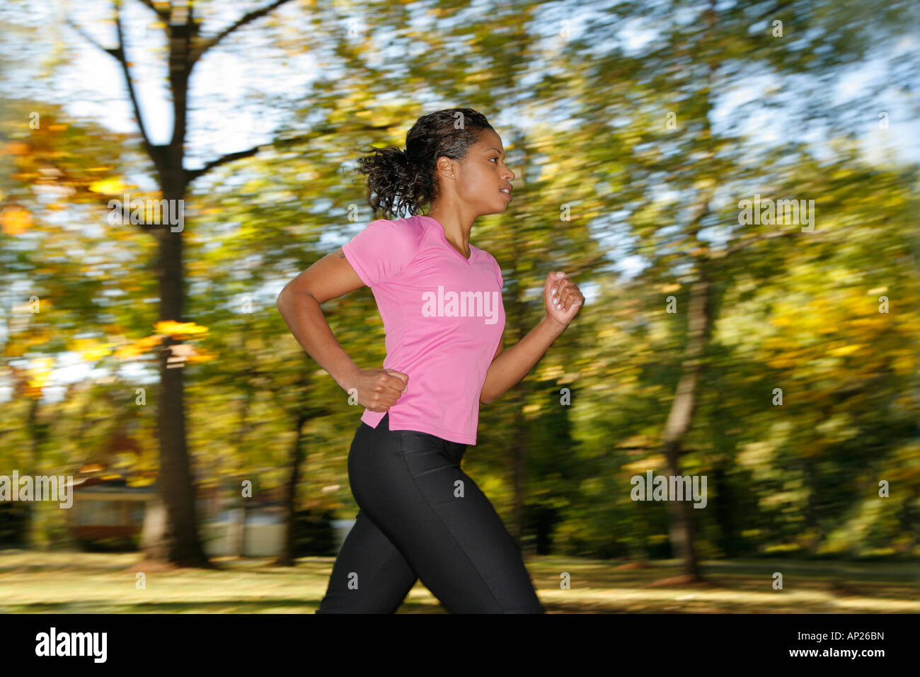 Young woman, jogging, running on a street with trees fall colors autumn ...