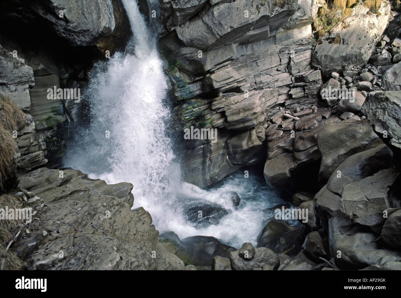 A WATERFALL flows past a cliff covered in plant life on the MODI RIVER ...