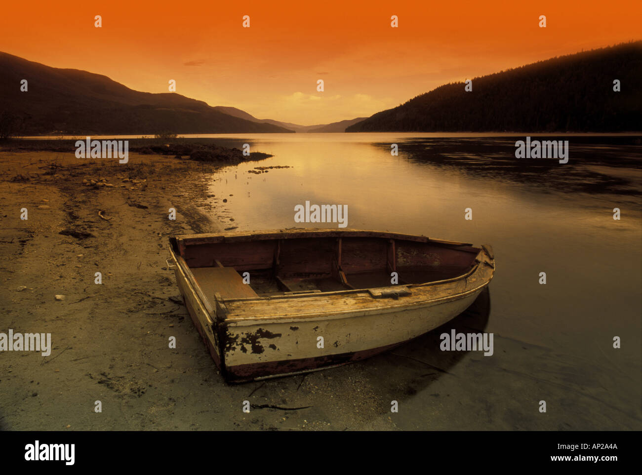 Row boat at water's edge against sunset backdrop Stock Photo - Alamy