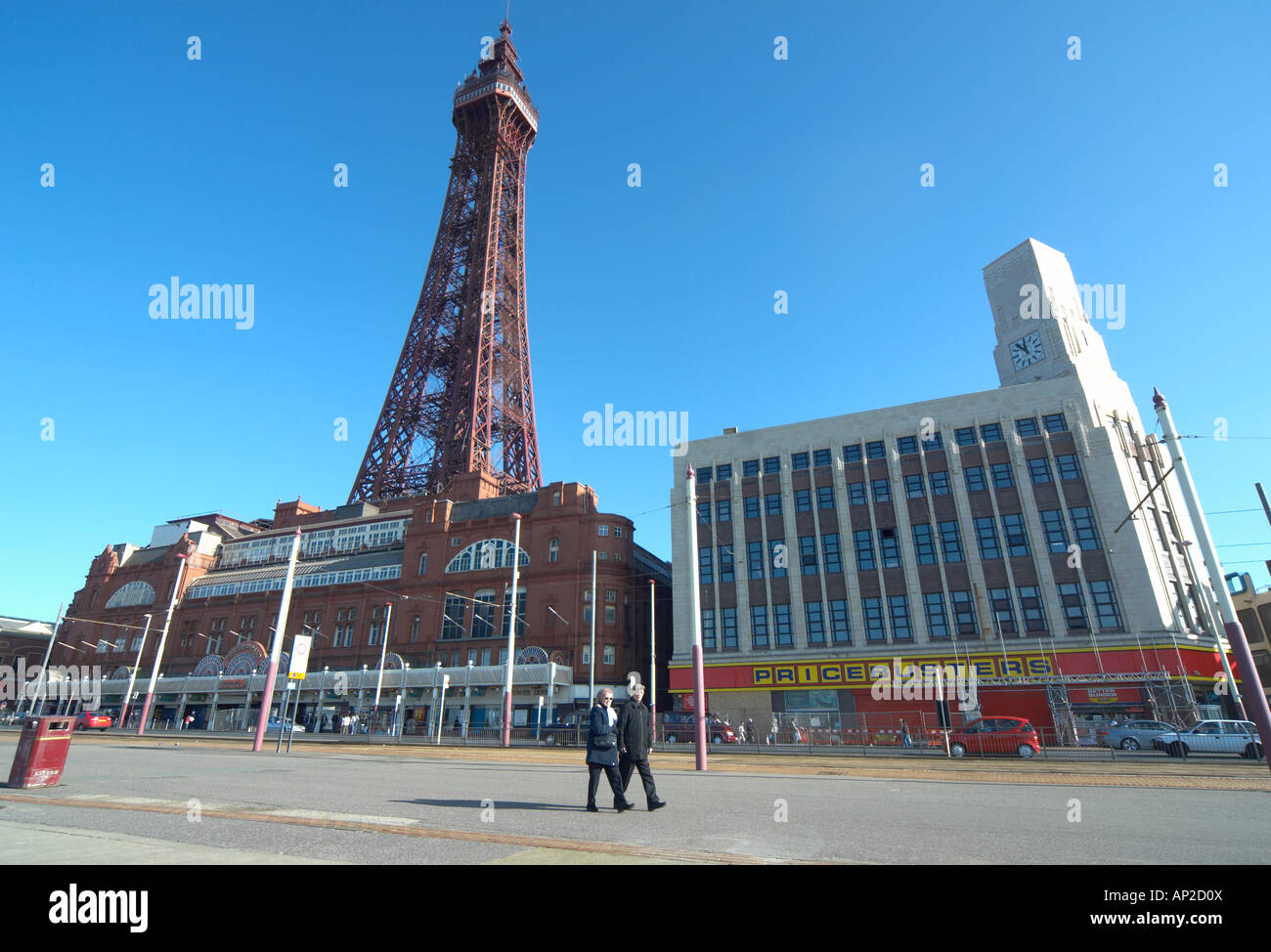 A couple walk along the promenade in front of Blackpool Tower in ...