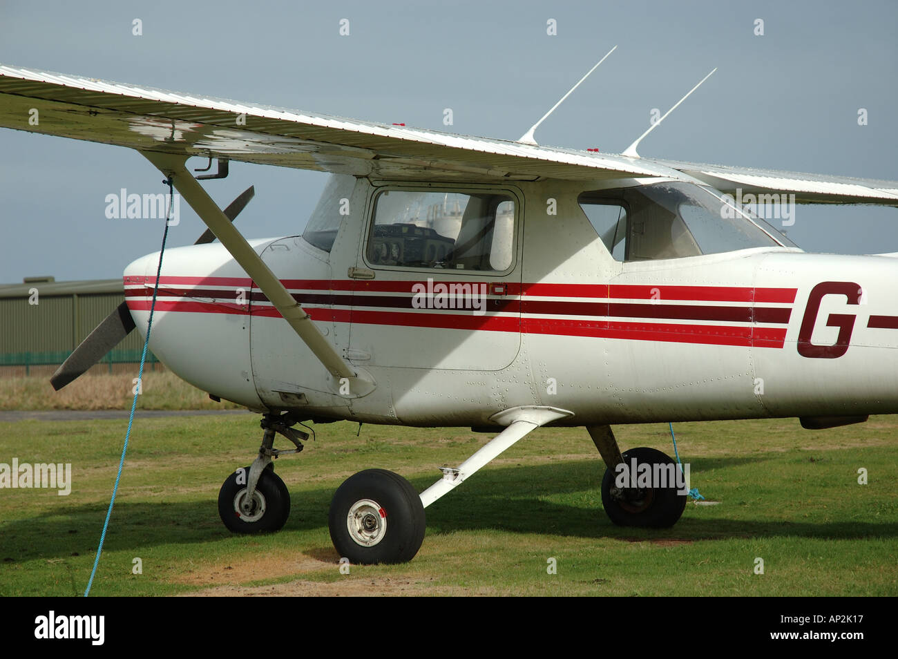 A small light aircraft pegged to the ground by ropes to prevent it ...