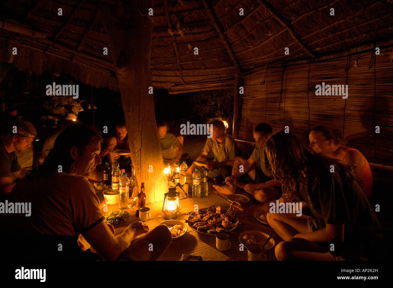 A group of people eating dinner in a typical hut, Madagascar, Africa ...