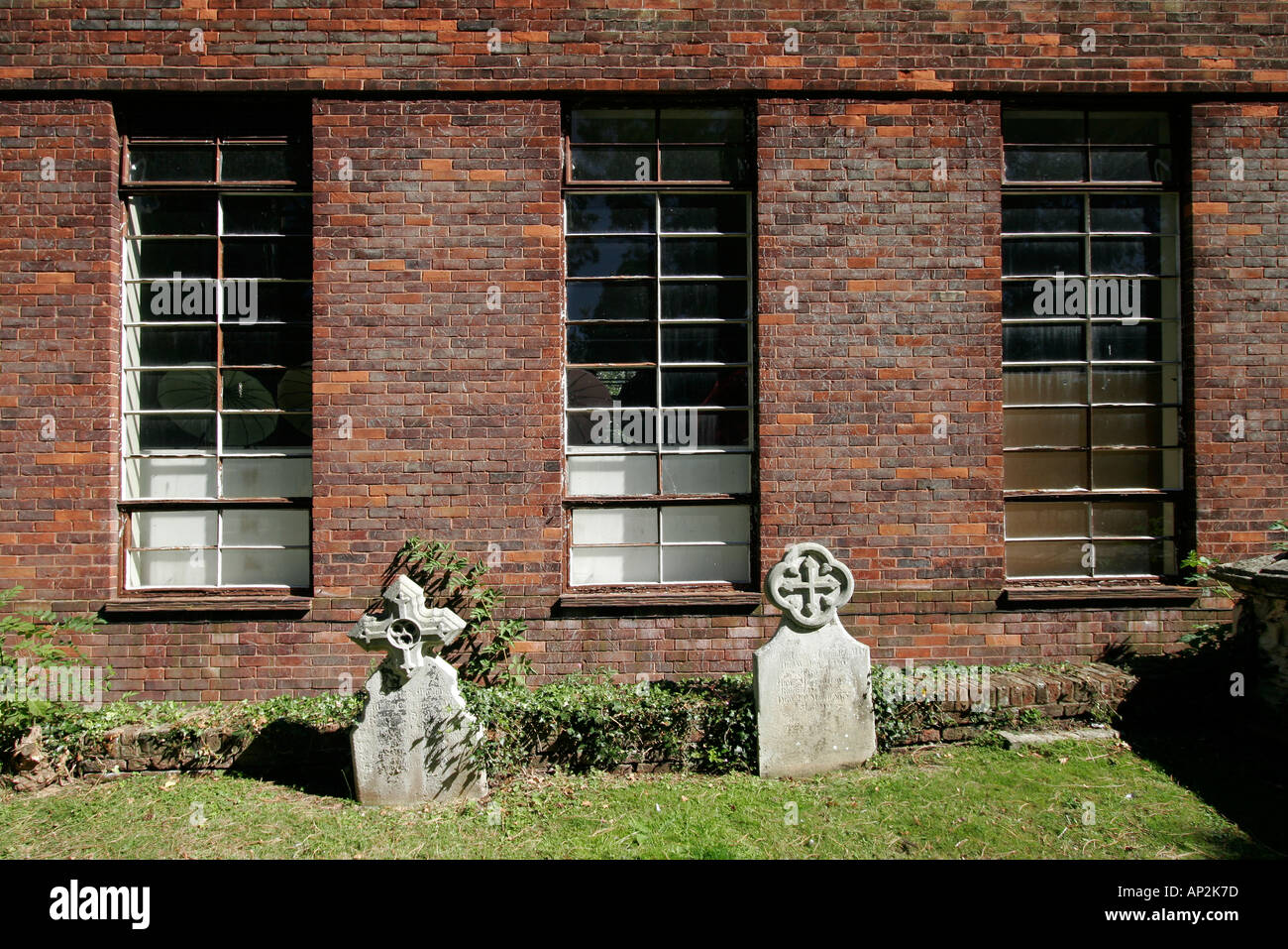 Two gravestones in churchyard with red brick industrial building in the ...