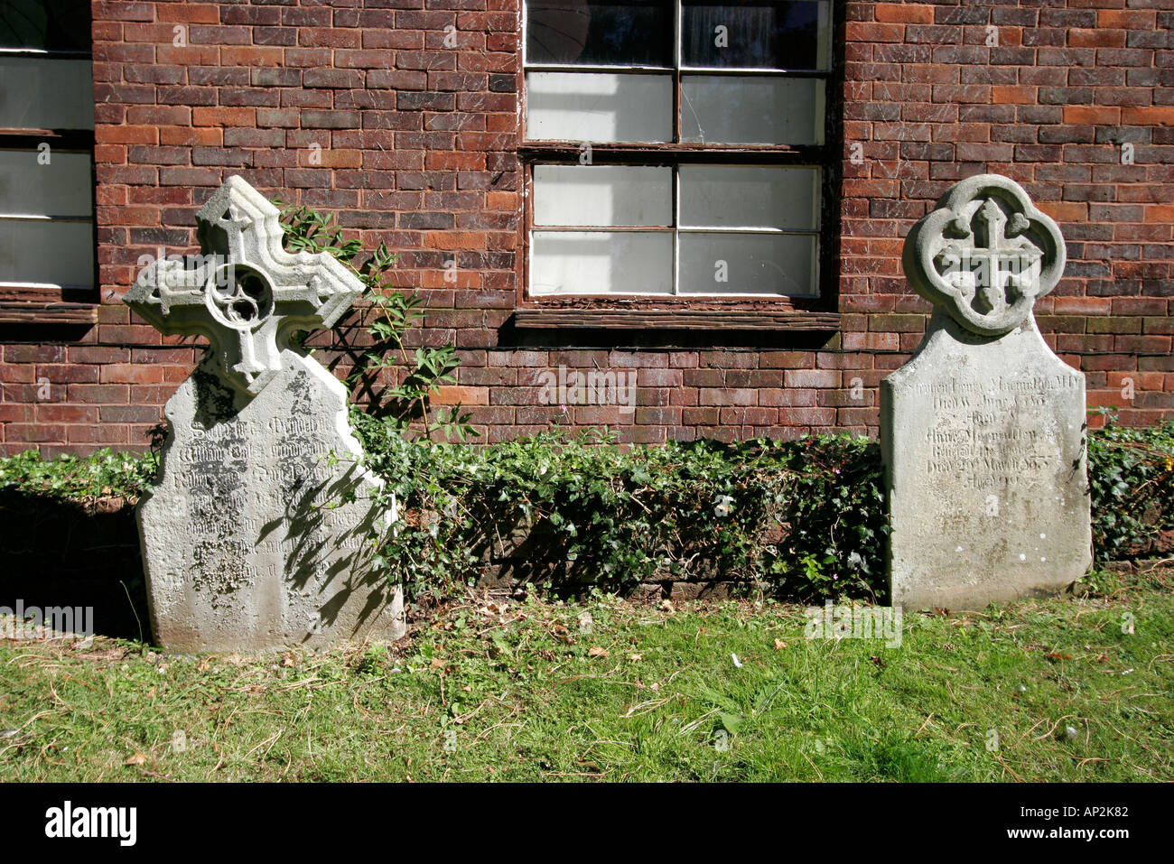 Two gravestones in churchyard with red brick industrial building in the ...