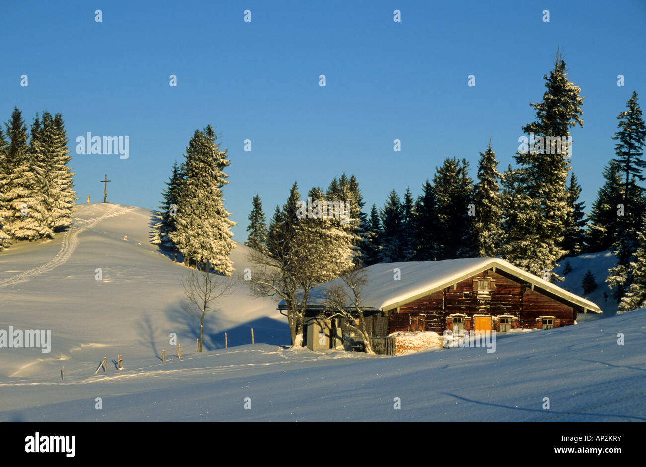 deeply snow-covered alpine hut of Huberalm and cross on summit of ...
