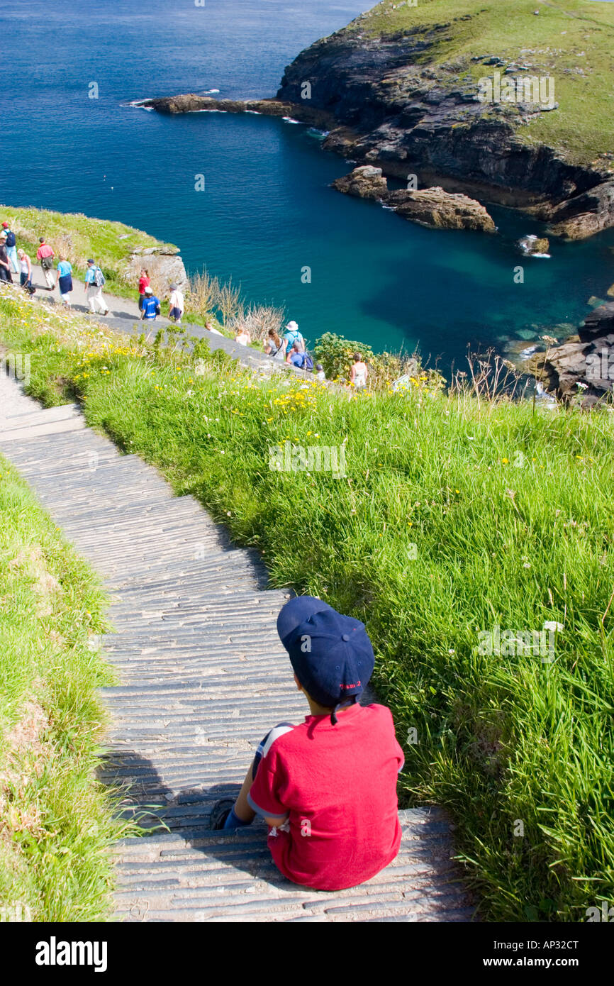 Small boy sitting paused at the top of a very steep flight of steps ...