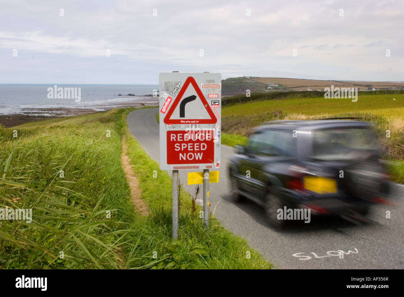 Car passing road sign warning of dangerous bend and Reduce speed now ...