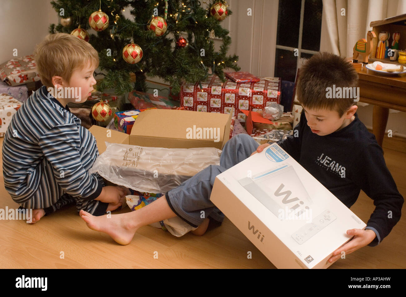 Two Boys Opening Presents Under Tree On Christmas Morning Stock Photo ...