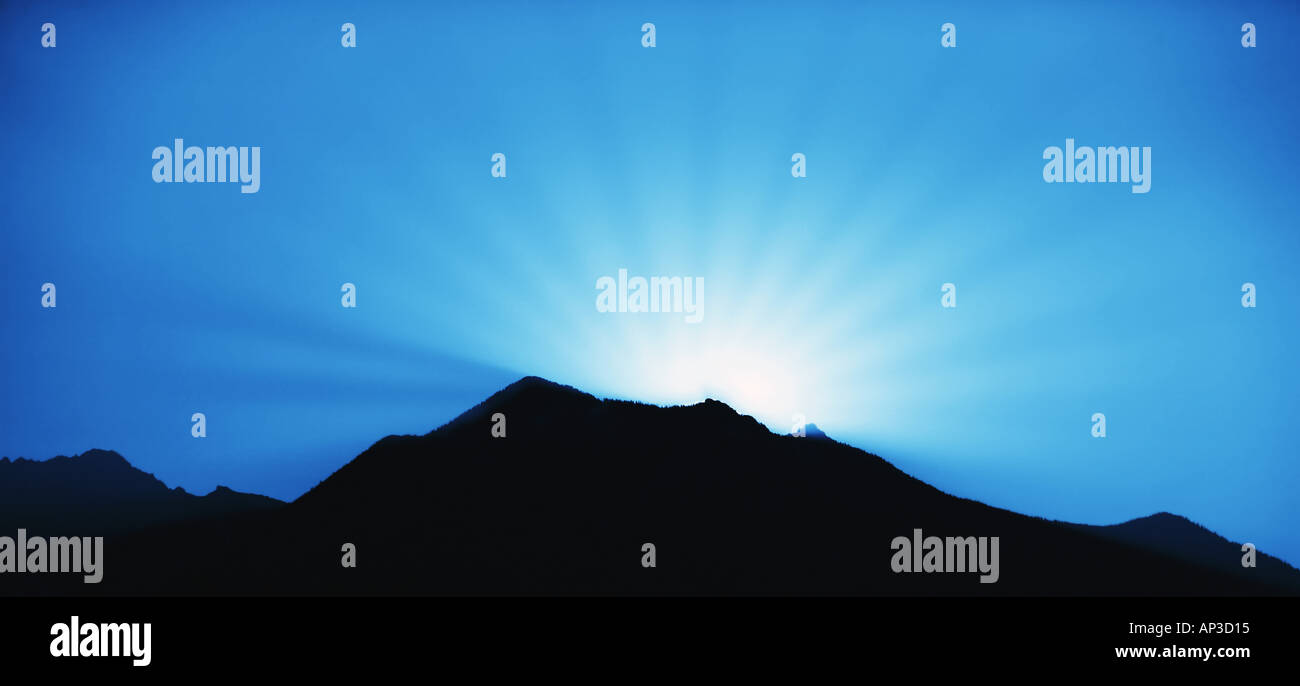 Sun rising behind mountain Stock Photo - Alamy
