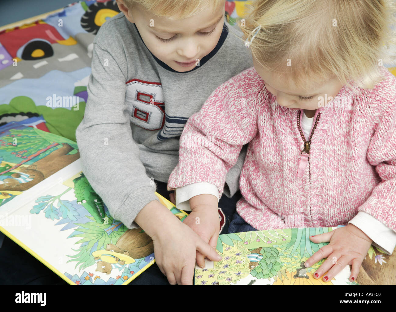Two children read a book Stock Photo - Alamy