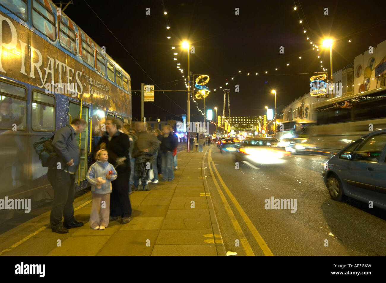 Tourists wait for a tram on the promenade at night during the world ...