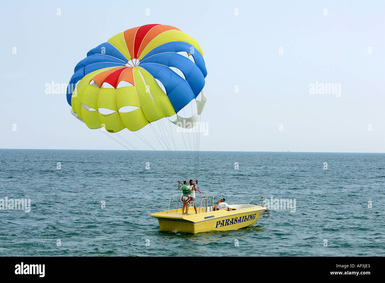 parachute paragliding behind a beach parasailing rainbow red yellow ...