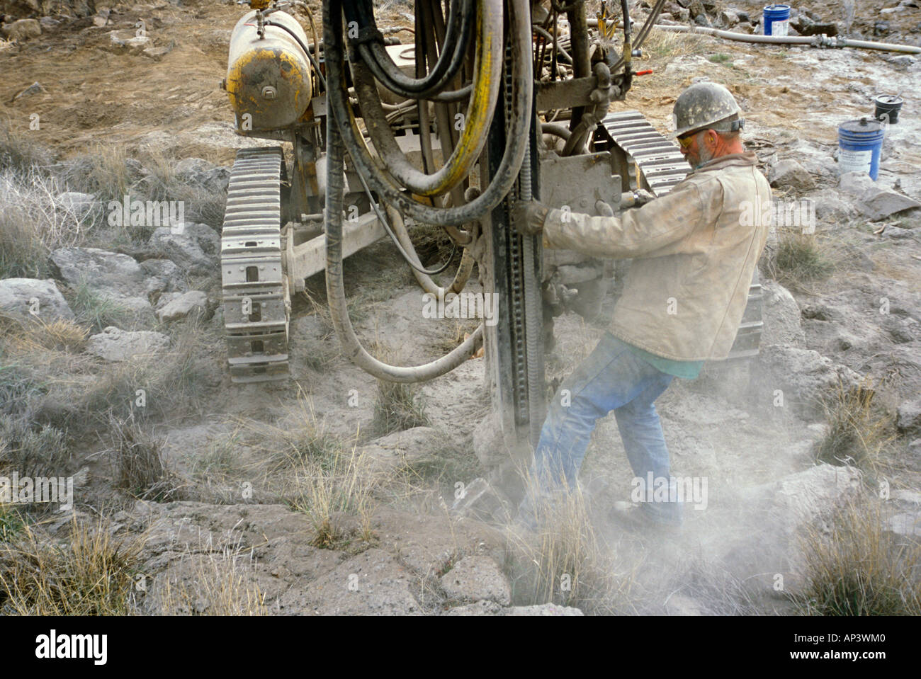A construction worker guides a hydraulic drill, as he uses it to break ...