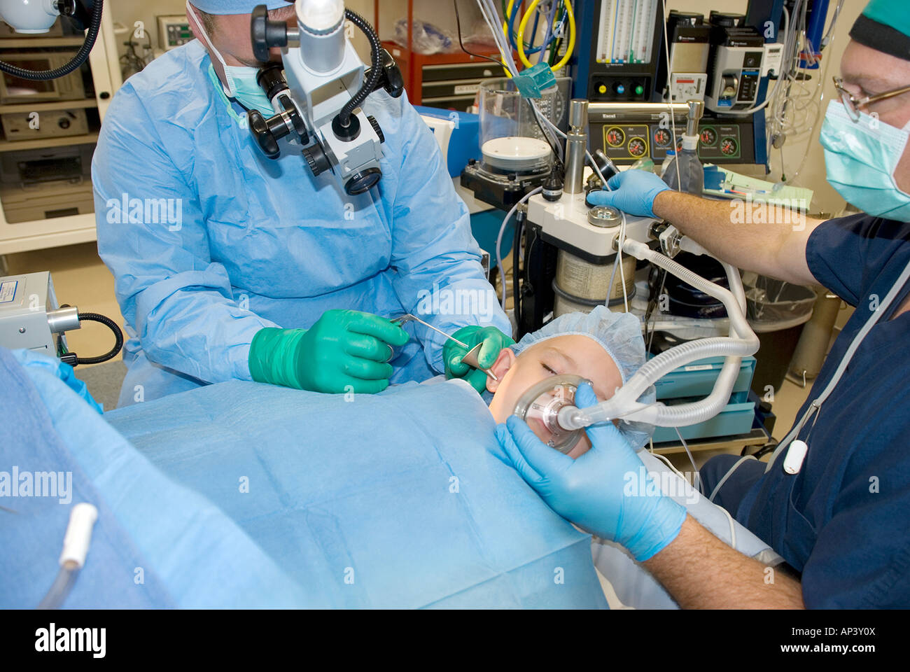 Surgical team performing ear surgery on young boy in hospital operating ...