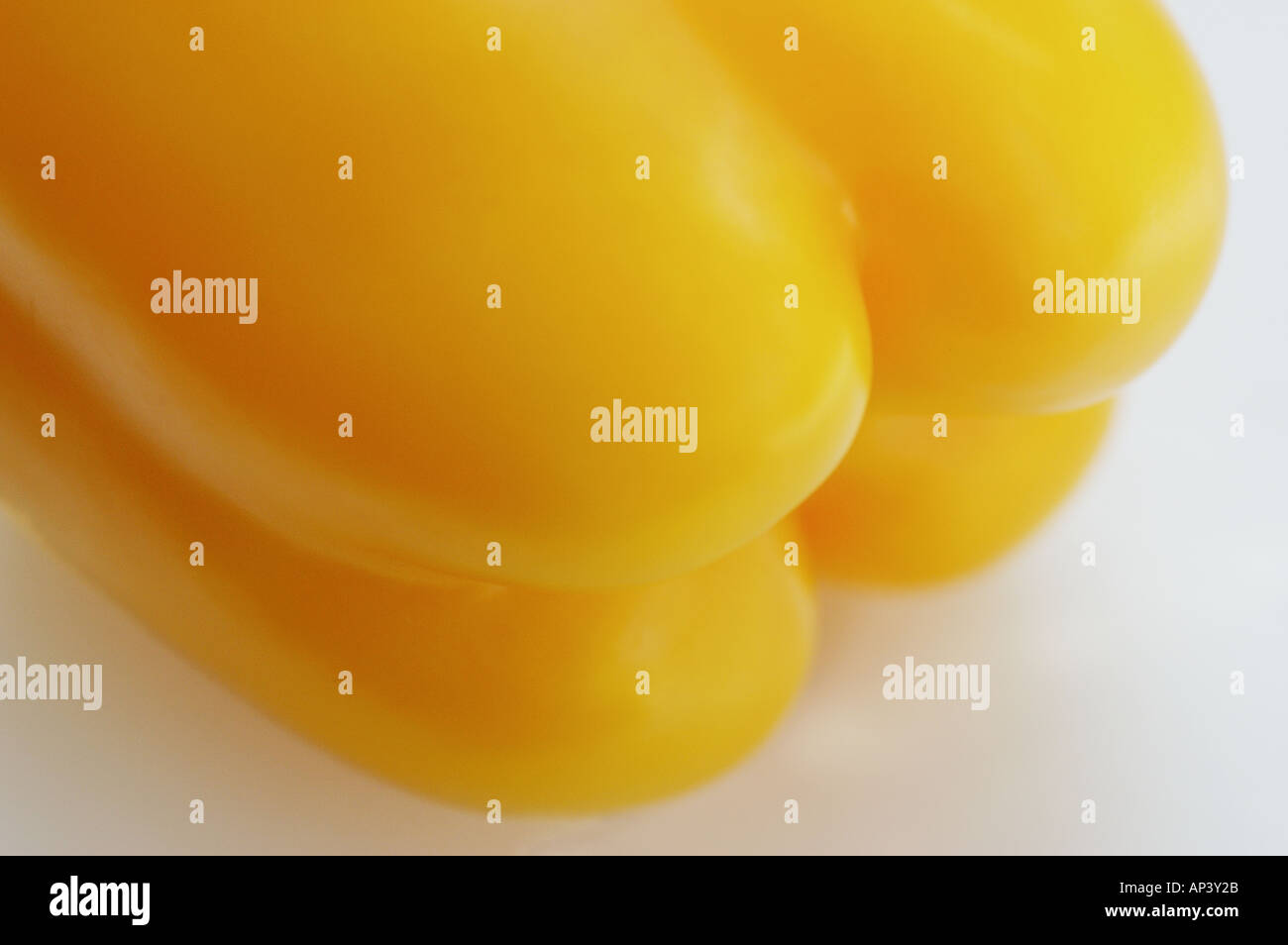 A yellow bell pepper proudly shows its bottom against an off-white ...
