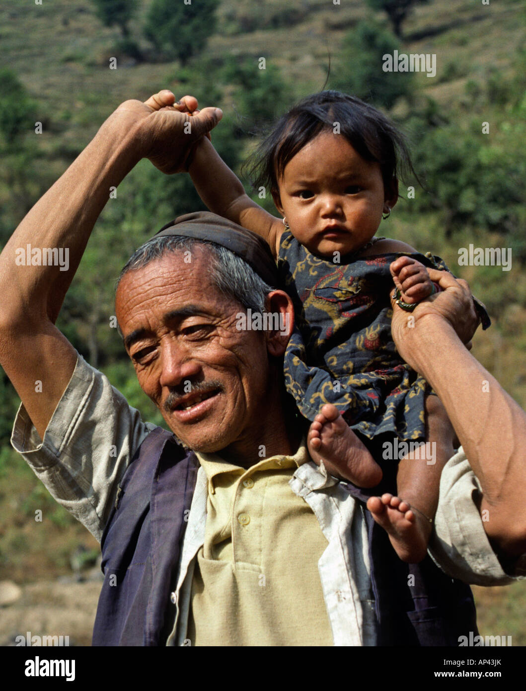 A GURUNG MAN holds a BABY GIRL on his shoulders in the DORDI RIVER VALLEY BODHA HIMAL NEPAL ...