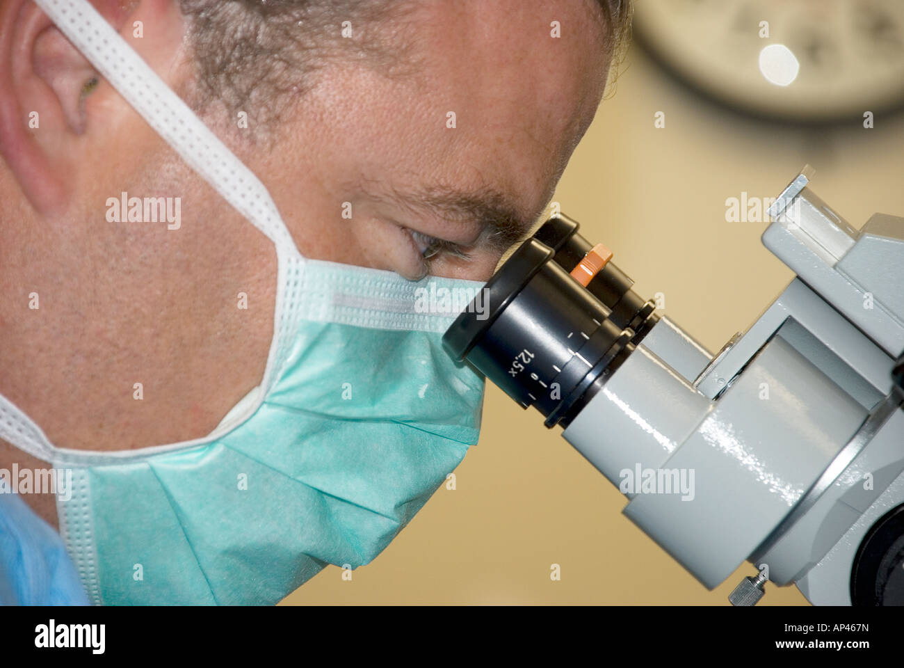 Surgeon looking through microscope while performing surgery in hospital ...