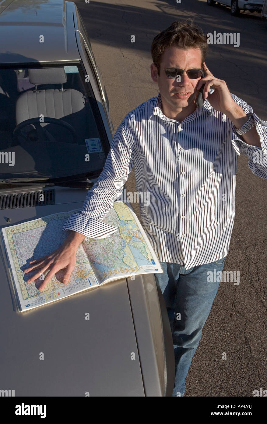 A man lost while driving checks a road map while on a cell phone Stock ...