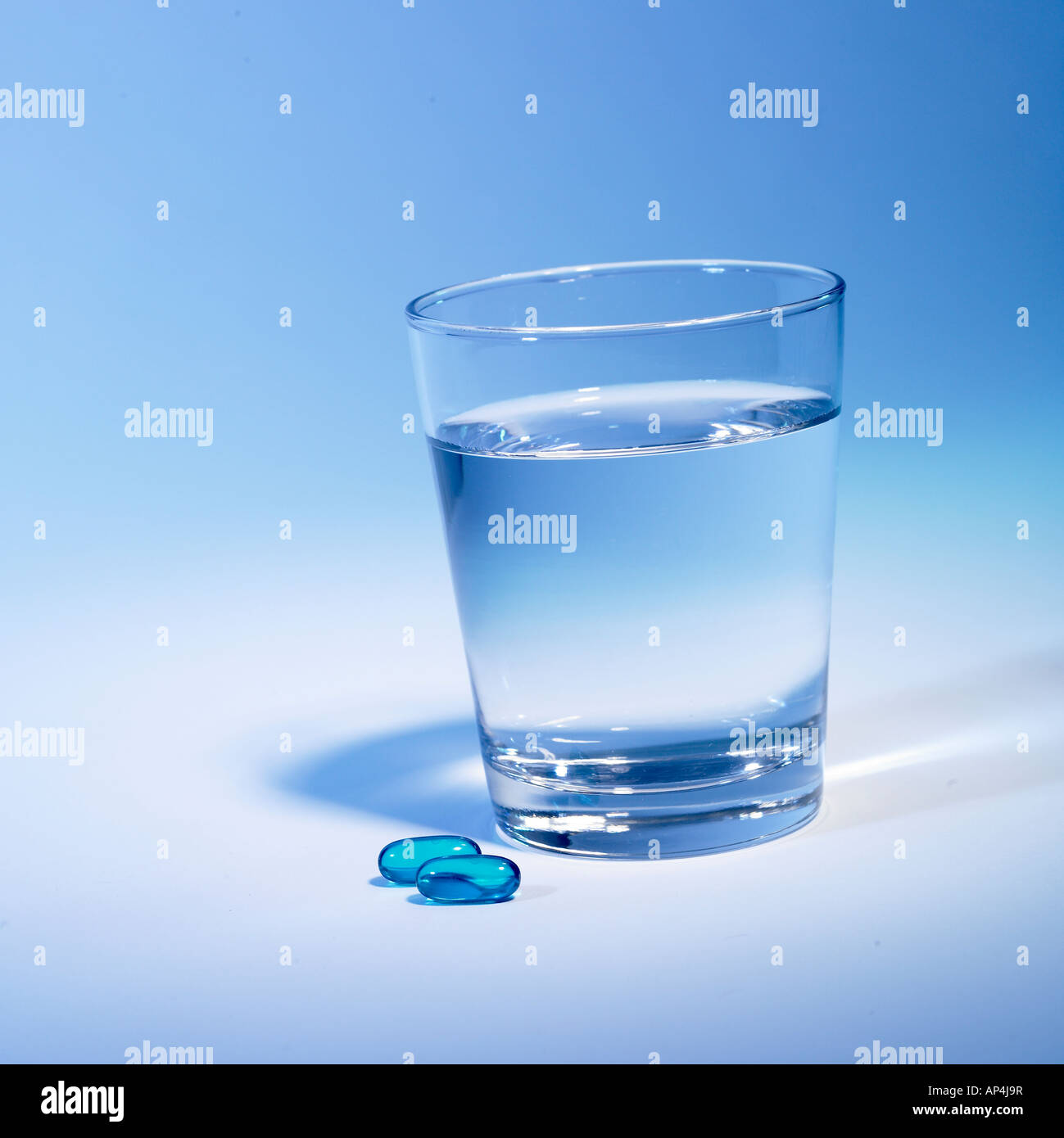 Glass of water with 2 capsules Stock Photo - Alamy