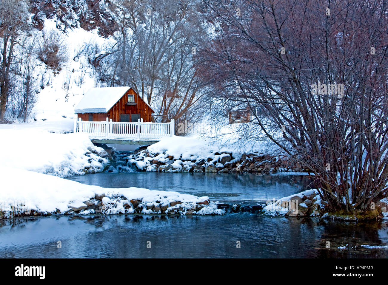 Cabin in winter snow on a small pond with footbridge Stock Photo - Alamy