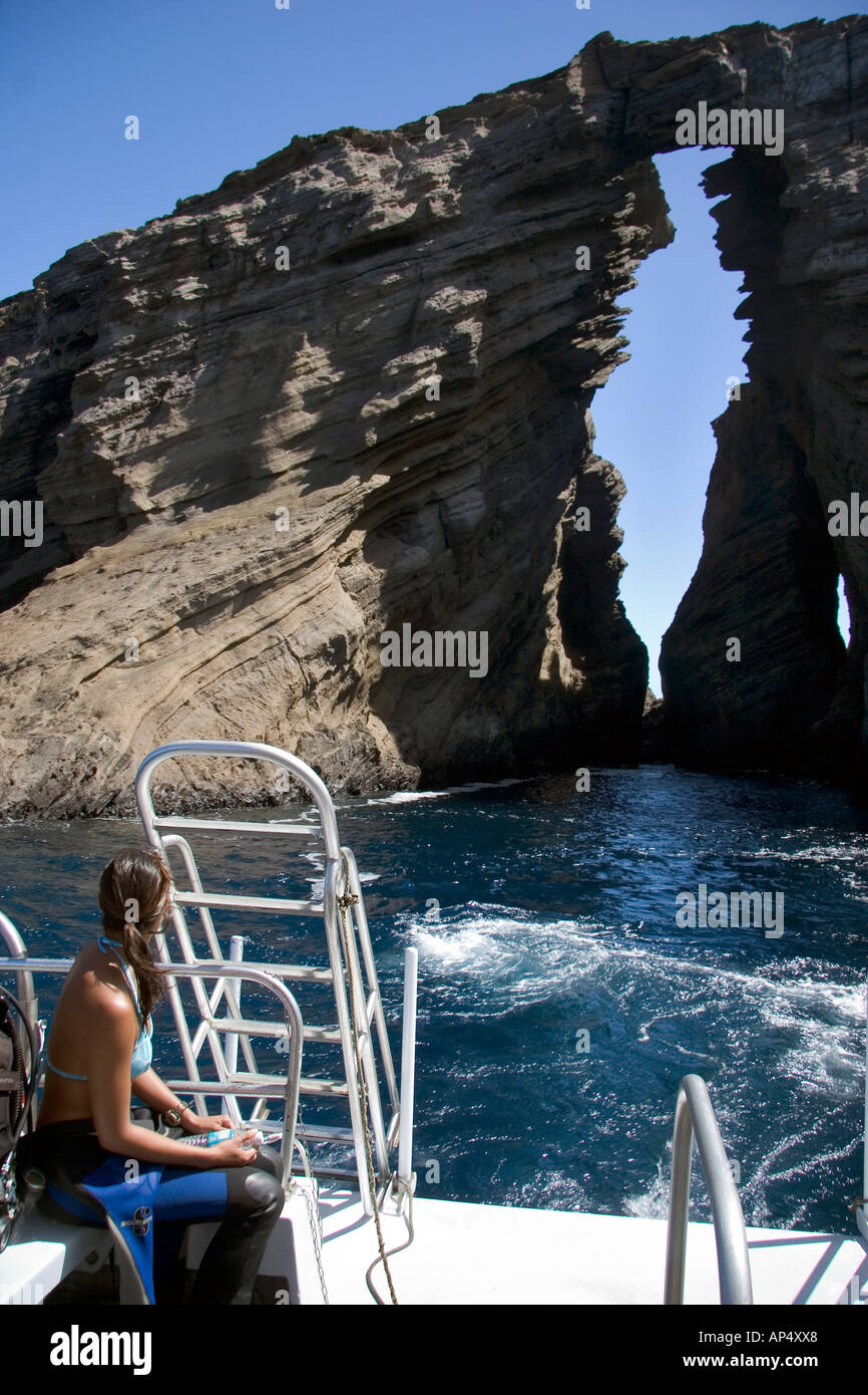 A dive charter vessel backs up to The Keyhole on Lehua Rock, a tuft ...