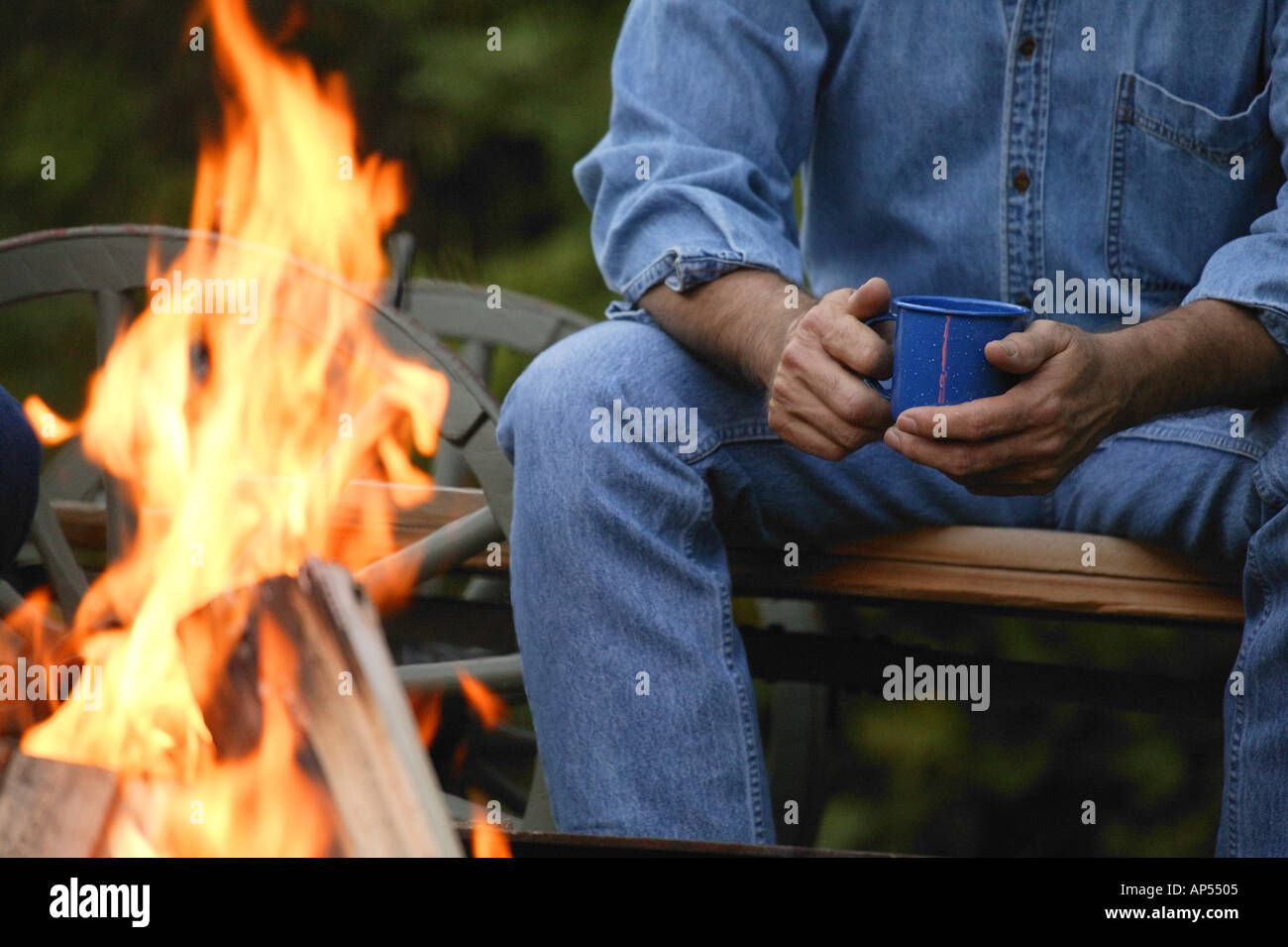 Man sitting by a fire Stock Photo - Alamy