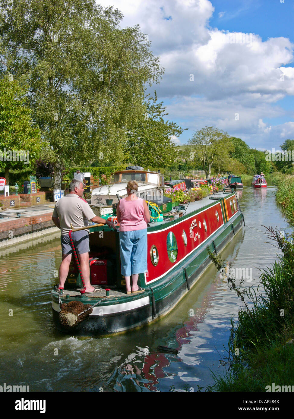 Man and woman steering a narrow boat along the Kennet Avon canal at ...