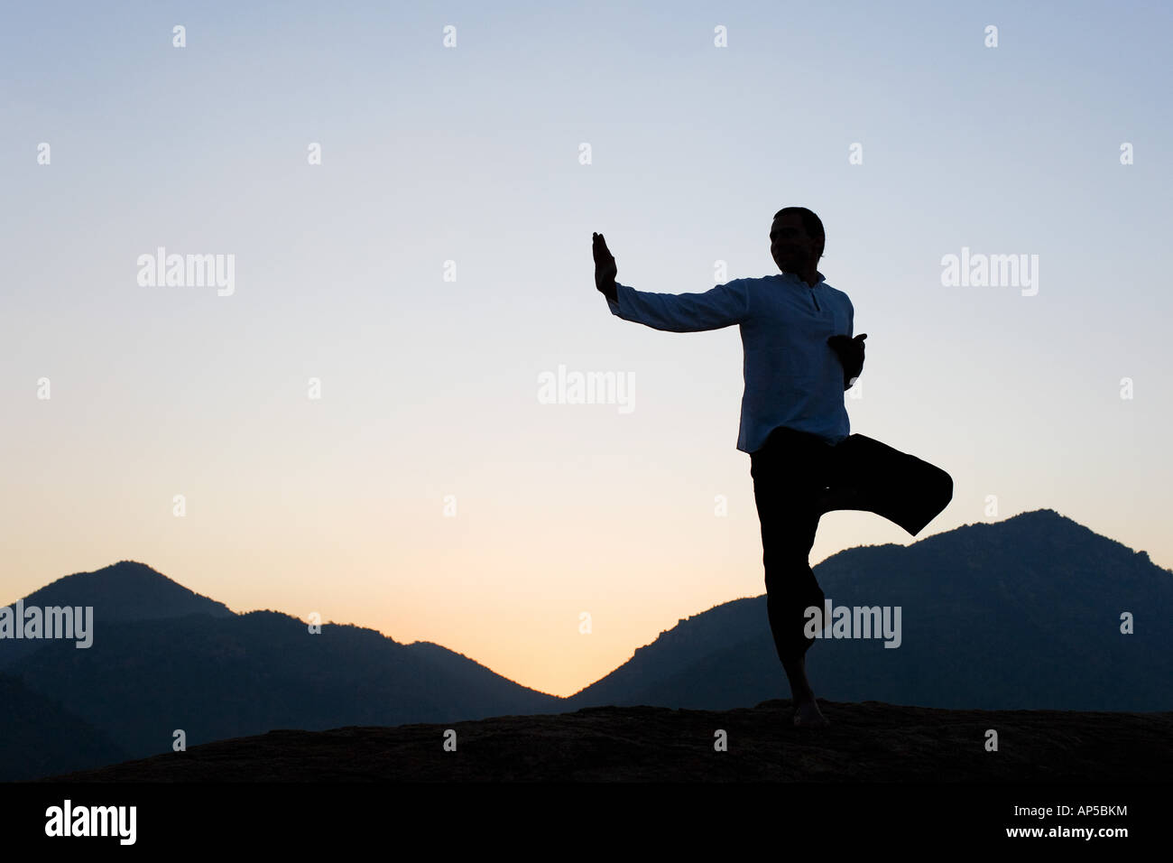 Man performing tai chi against a rising sun in india Stock Photo - Alamy
