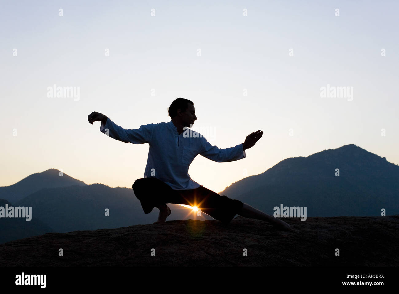 Man performing tai chi against a rising sun in india Stock Photo - Alamy