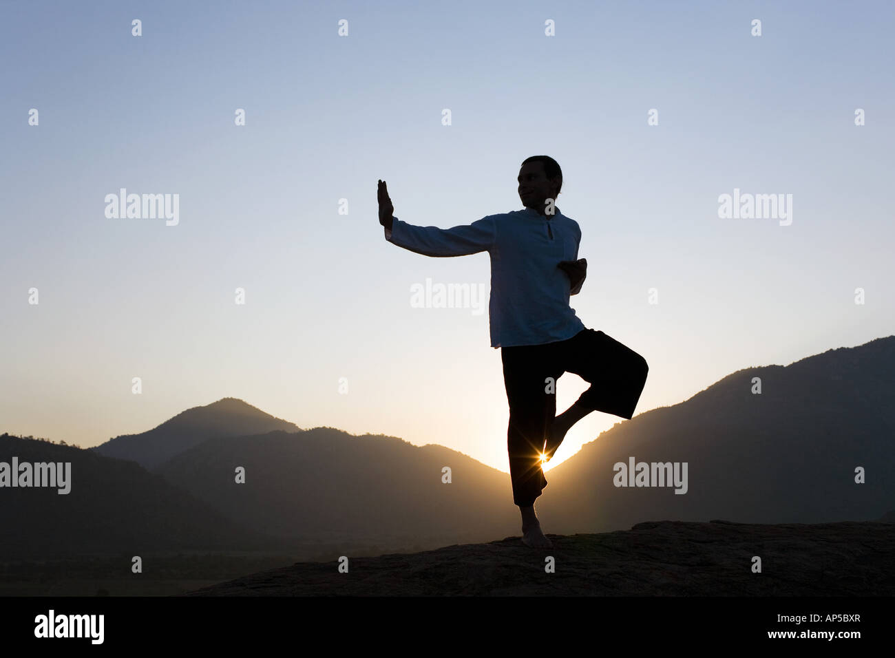Man performing tai chi against a rising sun in india Stock Photo - Alamy