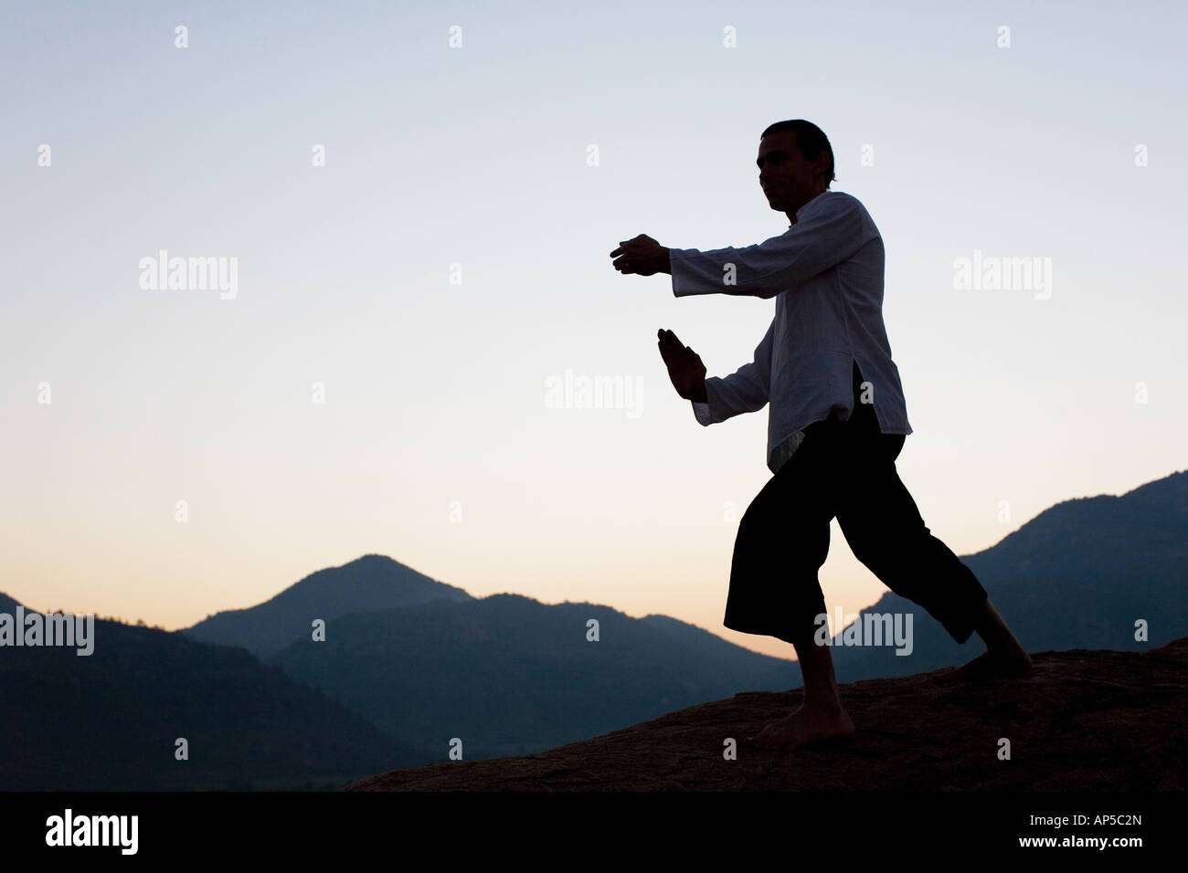 Man performing tai chi against a rising sun in india Stock Photo - Alamy
