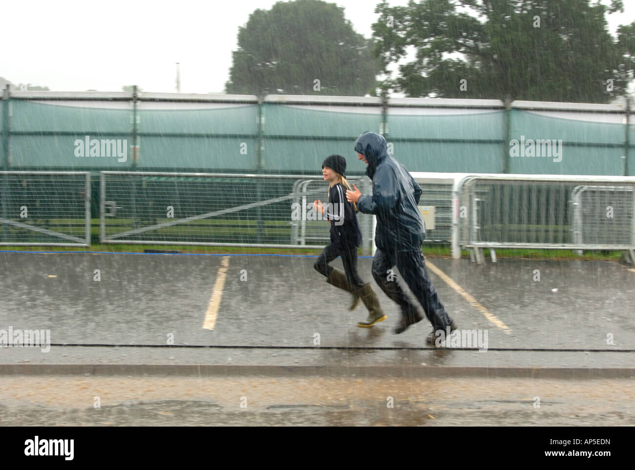 Two people running in a rain storm along a road in England Stock Photo ...