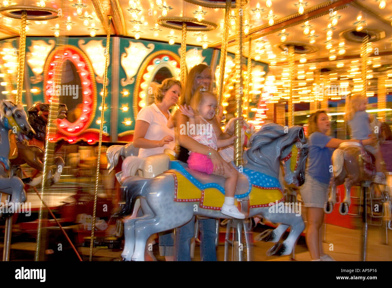 Children and adults ride a carousel at the Iowa state fair in Des ...