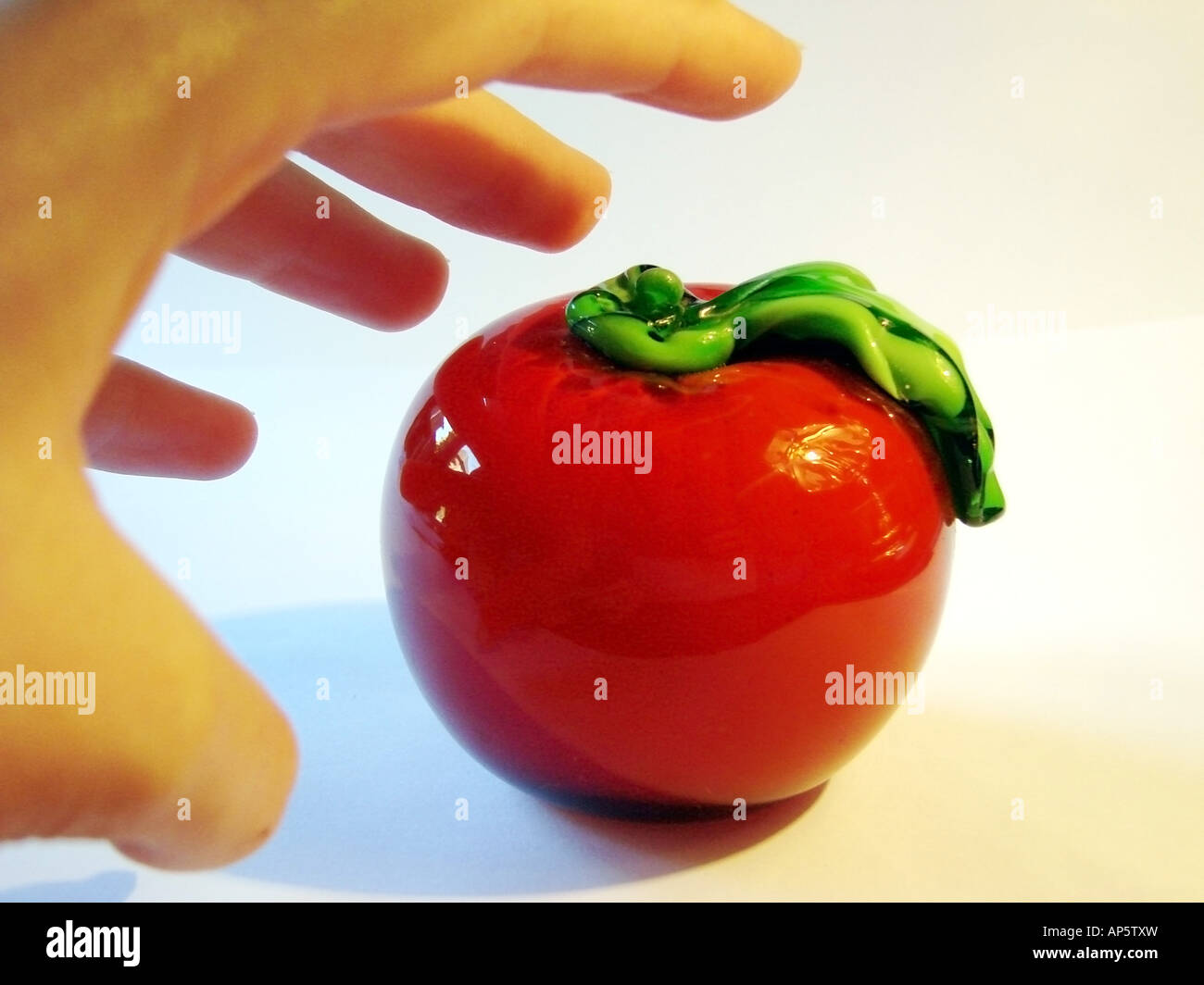 Reaching out to Grab hold of a Glass Tomato Stock Photo - Alamy