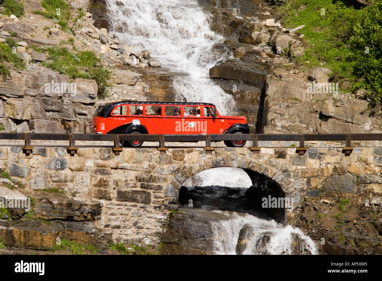 Red Jammer Bus crosses Haystack Creek in Glacier National Park in ...