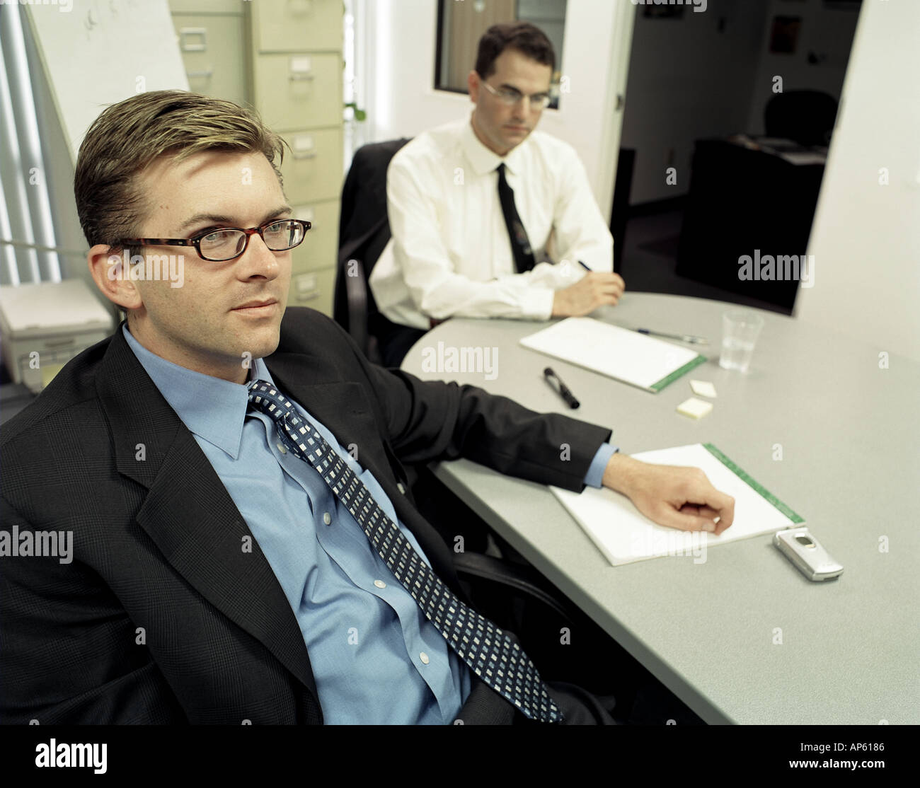 Two business men at table meeting and taking notes with presentation ...