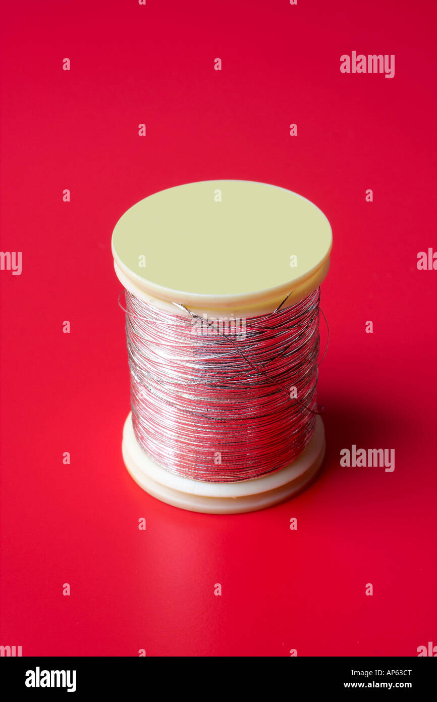 bobbin of thread on a red background Stock Photo - Alamy