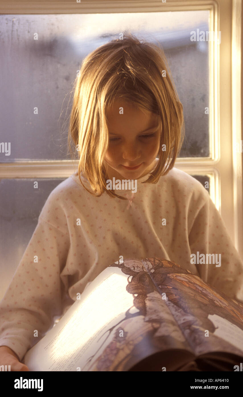 child reading a book in the window light Stock Photo - Alamy
