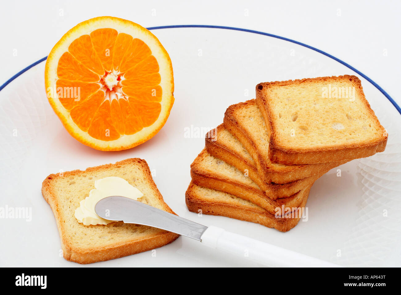 Toast with butter and half orange on white plate Stock Photo - Alamy