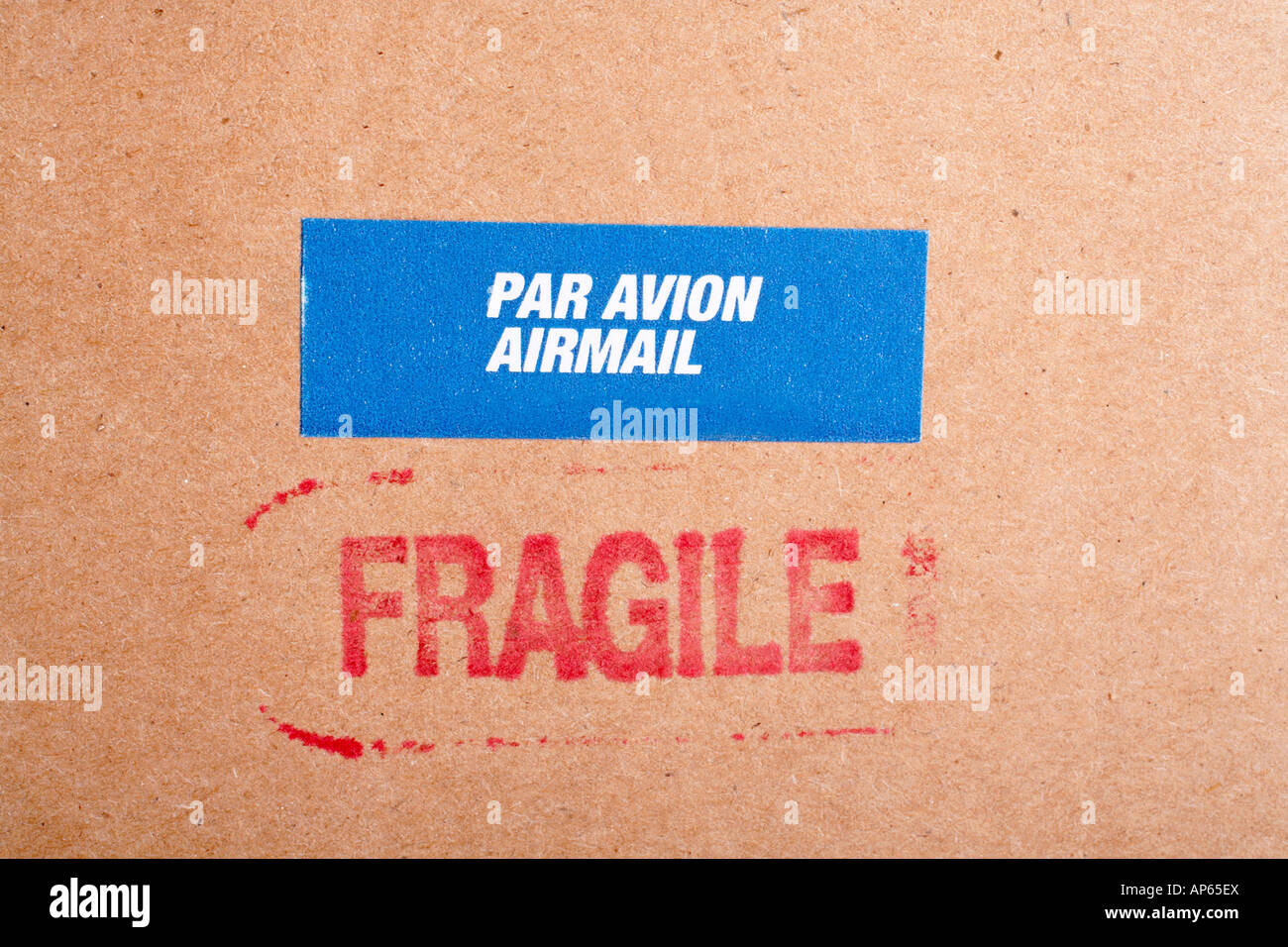Fragile on cardboard box and par avion airmal sticker Stock Photo - Alamy