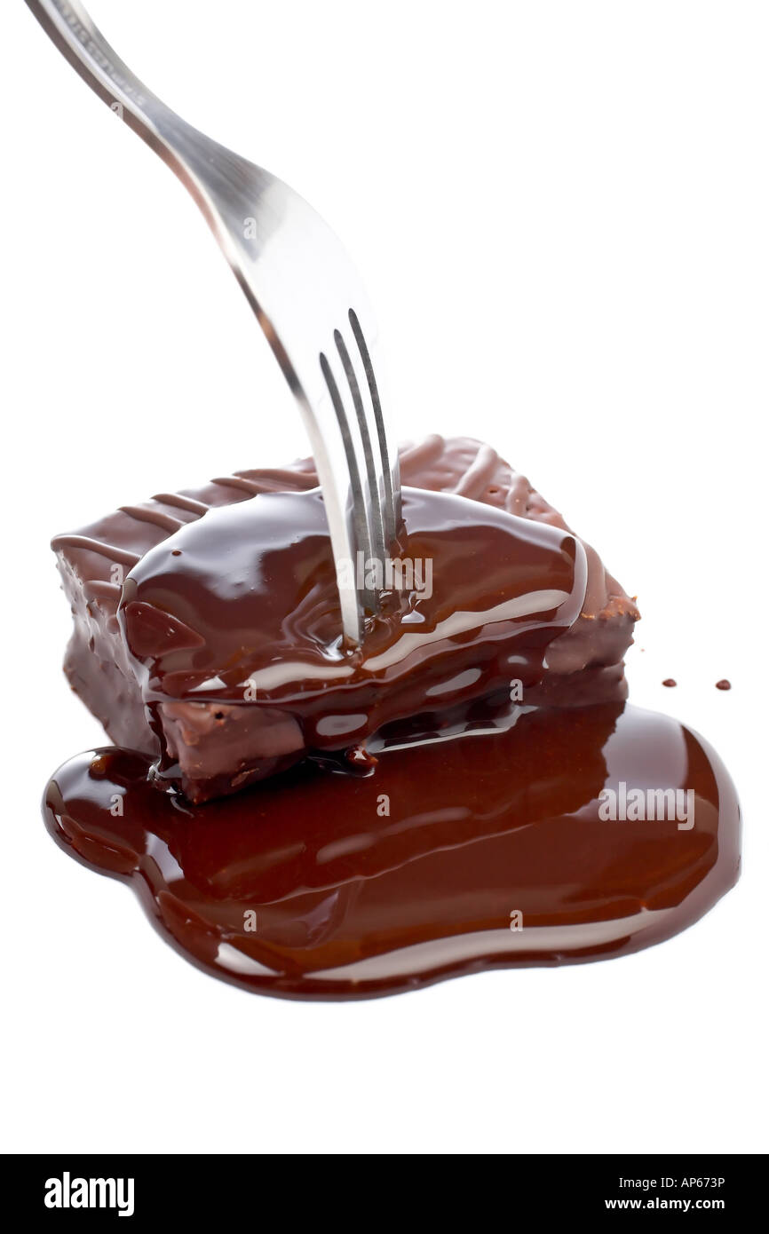 The fork pricking a chocolate cake with syrup on white background Stock ...