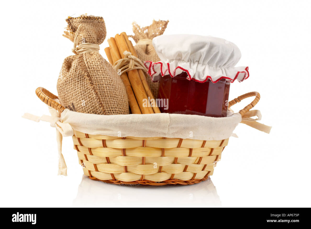 Jam jar sticks of cinnamon and burlap in a basket reflected on white ...