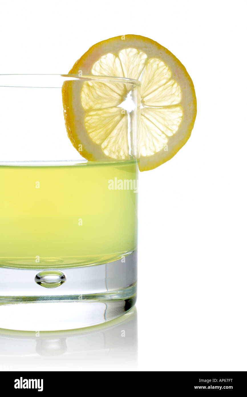 A glass of fresh lemon juice with a slice reflected on white background ...