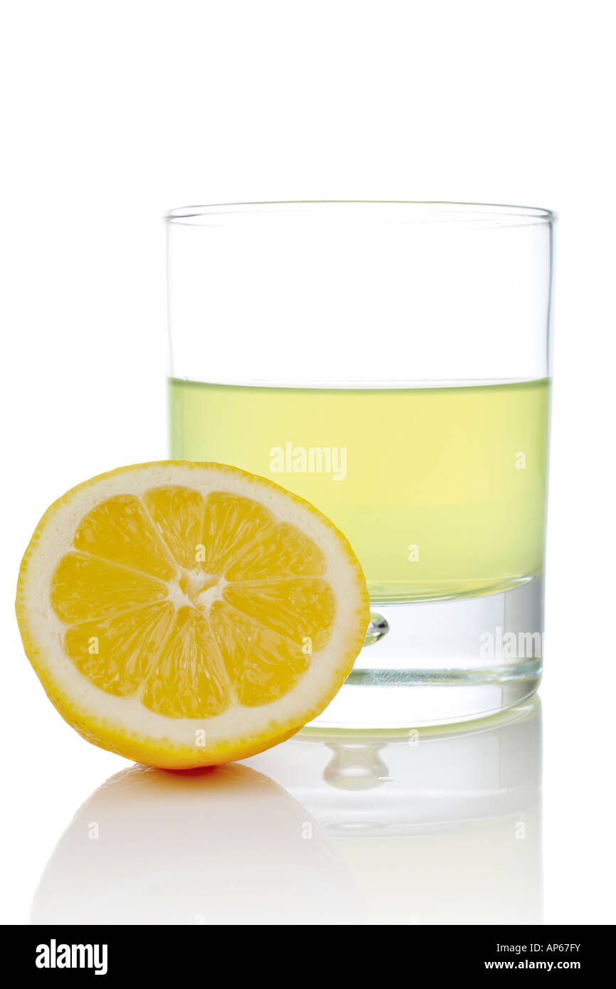 A half and glass of fresh lemon juice reflected on white background ...