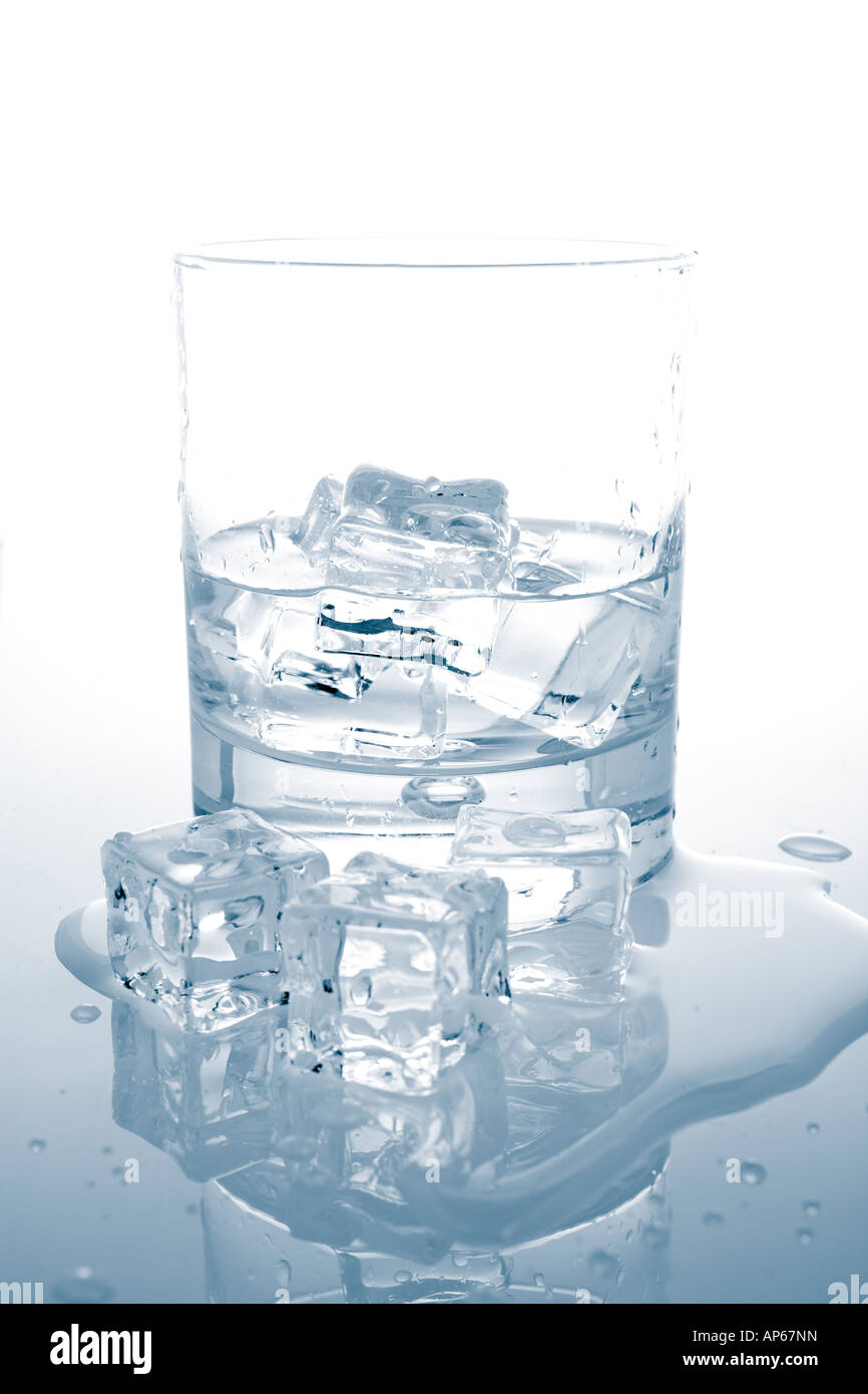 Glass of fresh mineral water with ice cubes reflected on wet background ...