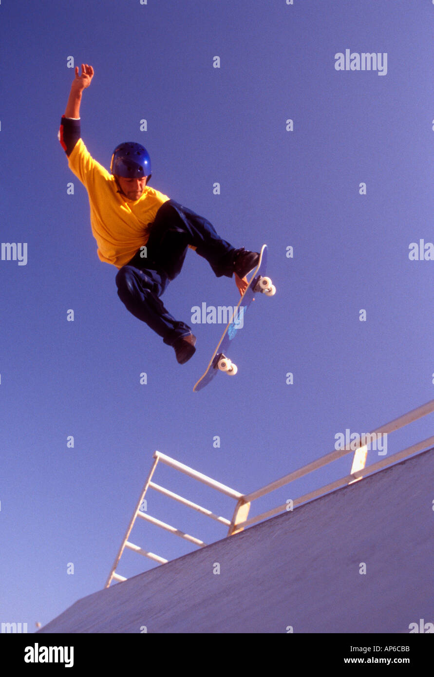 Skateboarder mid air wearing safety equipment flies up in freeze frame ...